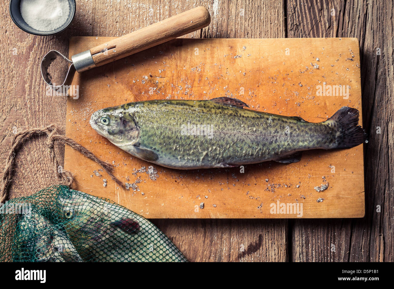 Preparing freshly caught trout on an old wooden chopping board Stock ...