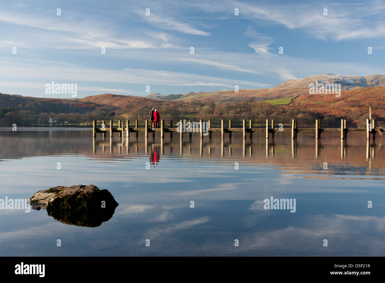 A couple stand admiring the view from a jetty which extends over ...