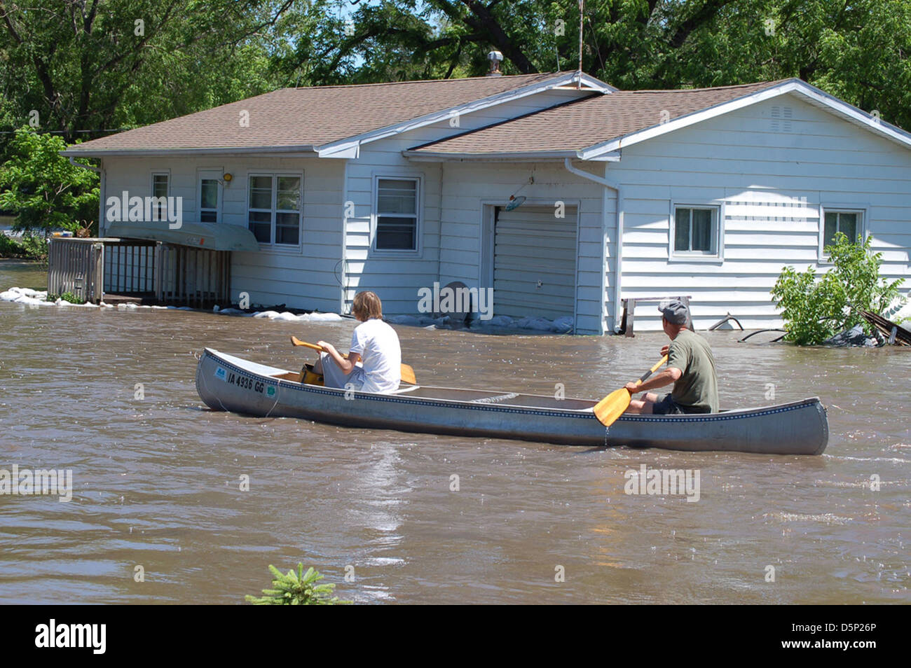 This image depicts a canoe on the waters of Iowa during a flood event ...