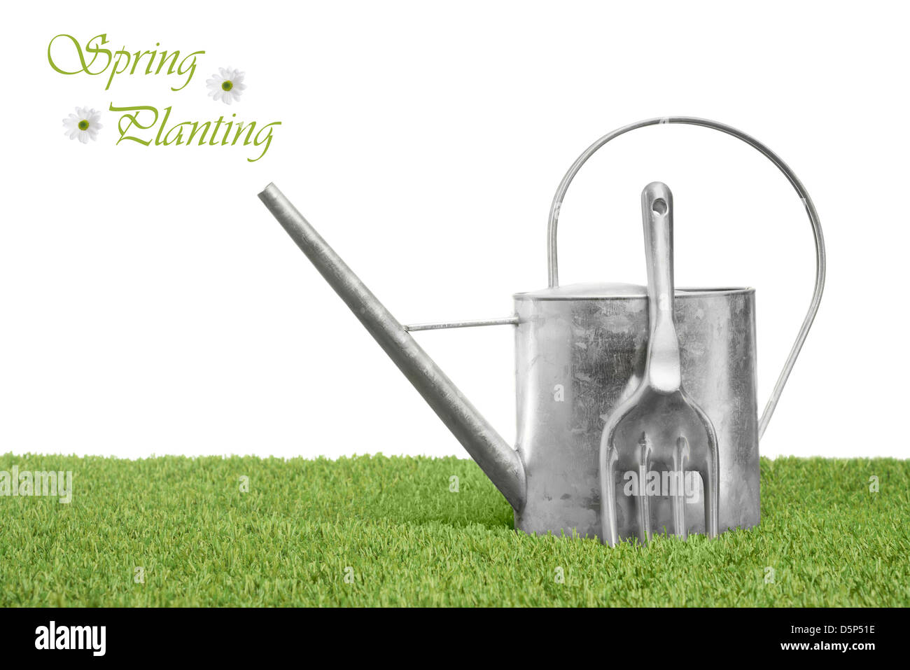 Spring planting time with watering can and garden fork on grass with ...