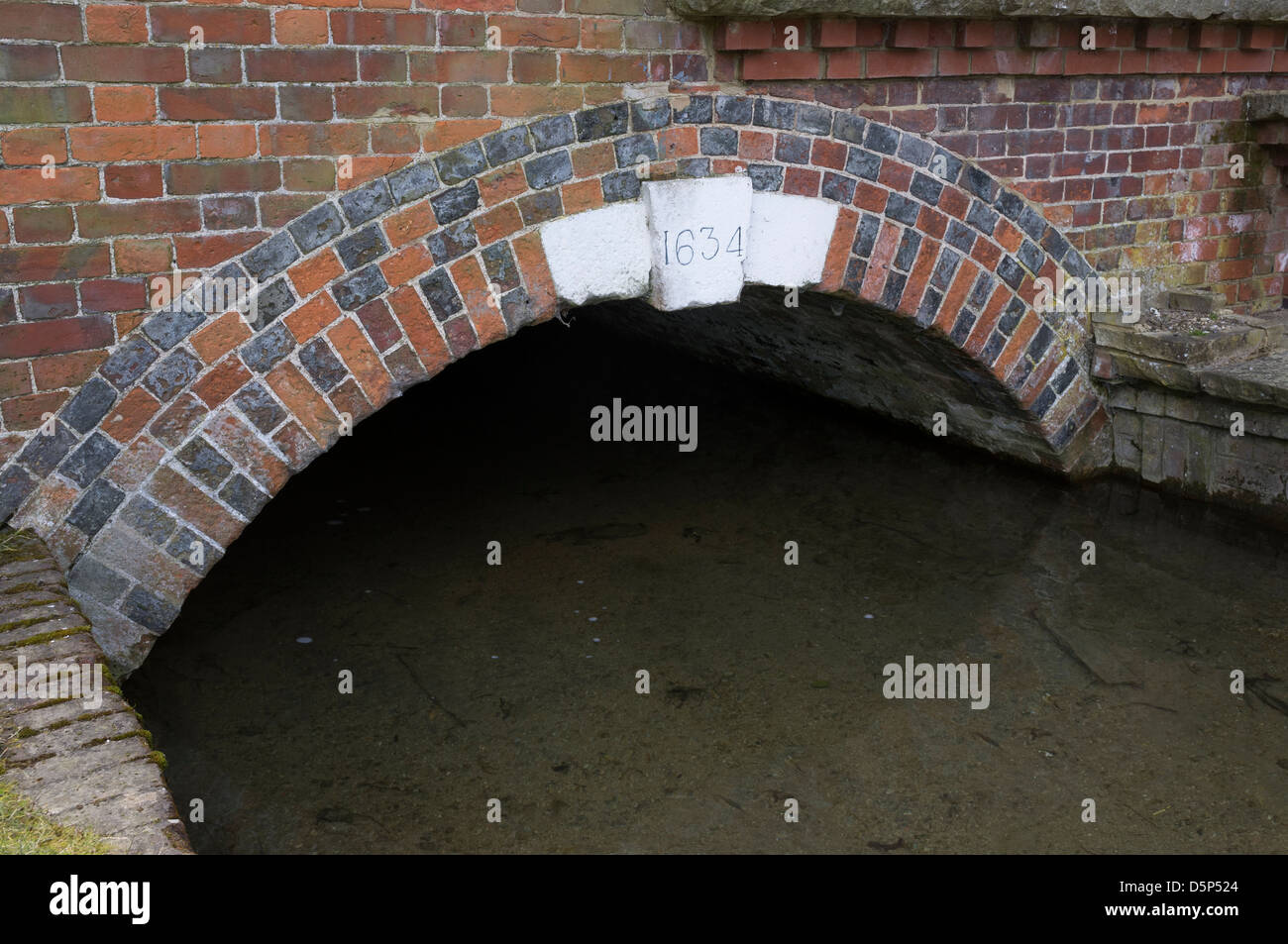 River Misbourne flows under a low brick built arched bridge part of ...