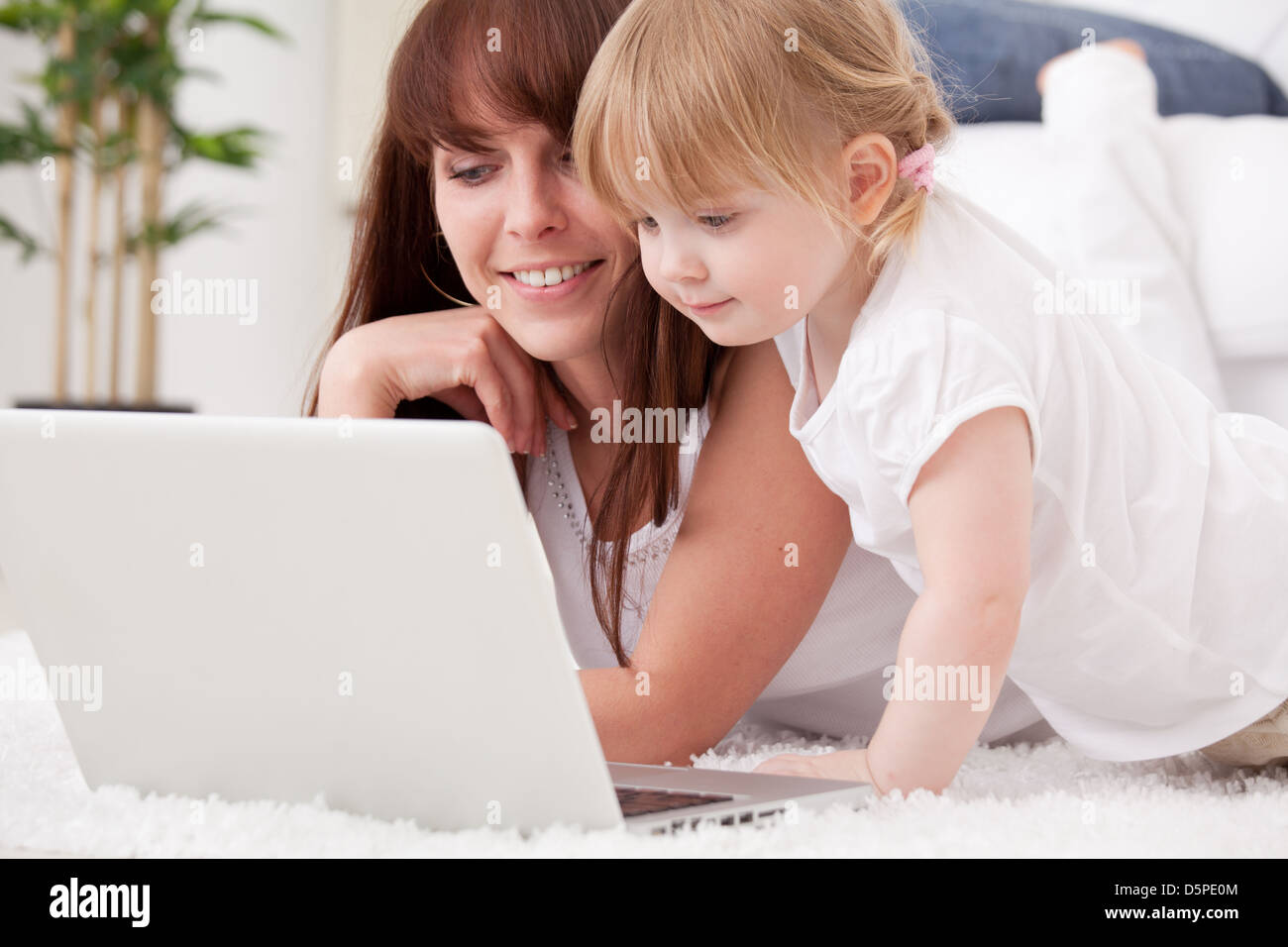 Happy young mother and her daughter using a laptop Stock Photo - Alamy