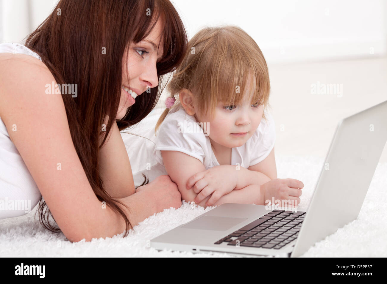 Happy young mother and her daughter using a laptop Stock Photo - Alamy