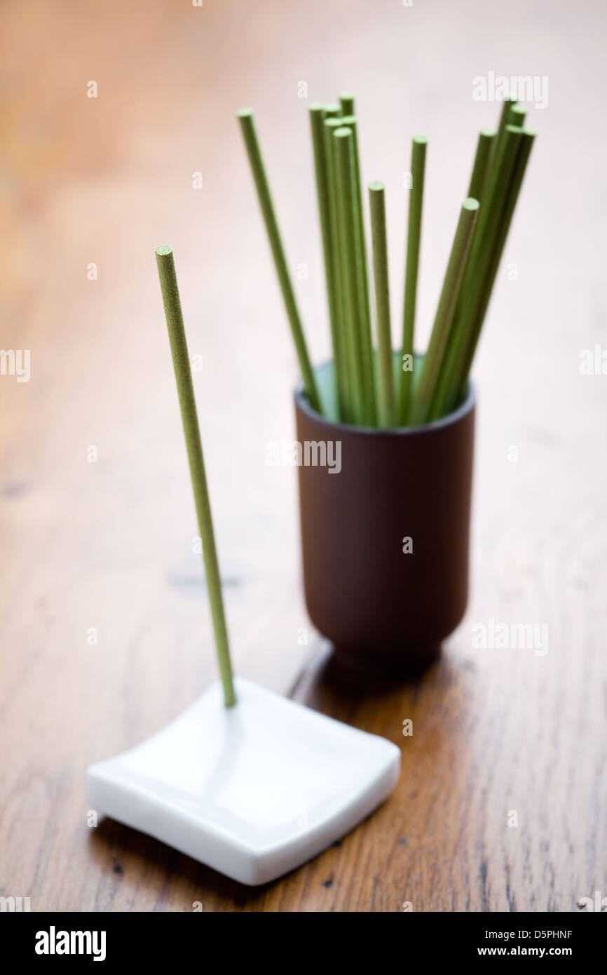 Green incense sticks on brown wooden table Stock Photo - Alamy
