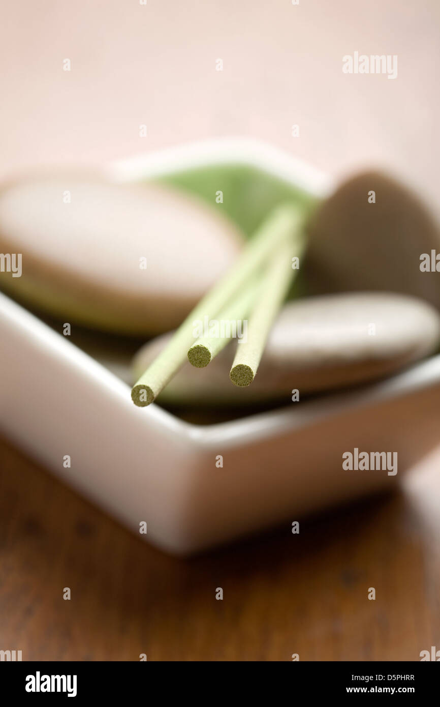 Green incense sticks and massage stones on bowl Stock Photo - Alamy