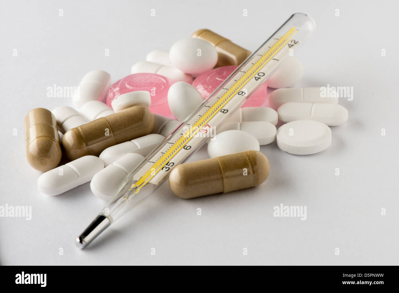 Pile of pills with thermometer Stock Photo - Alamy