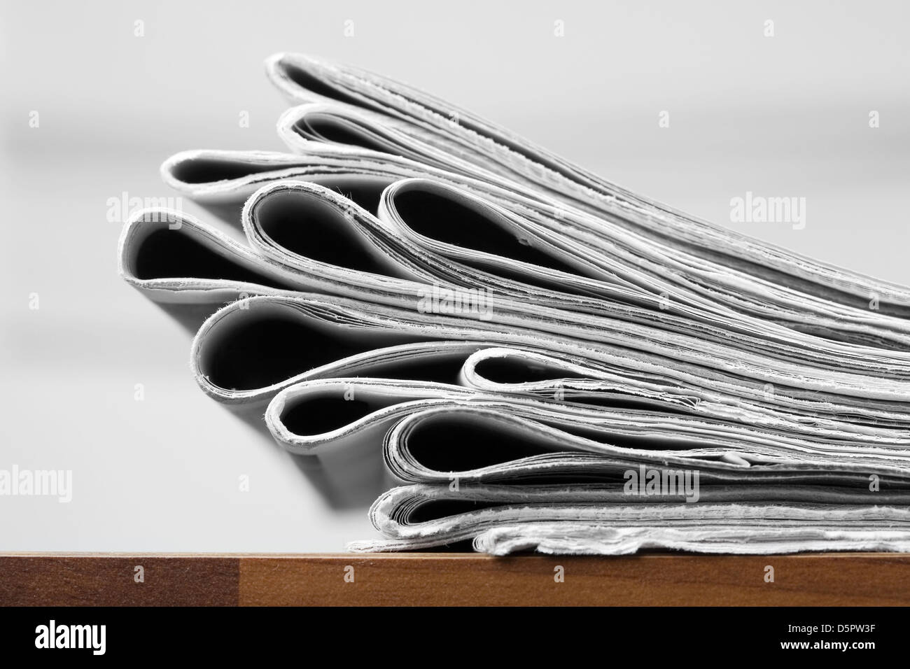 Folded newspapers on brown wooden table Stock Photo - Alamy
