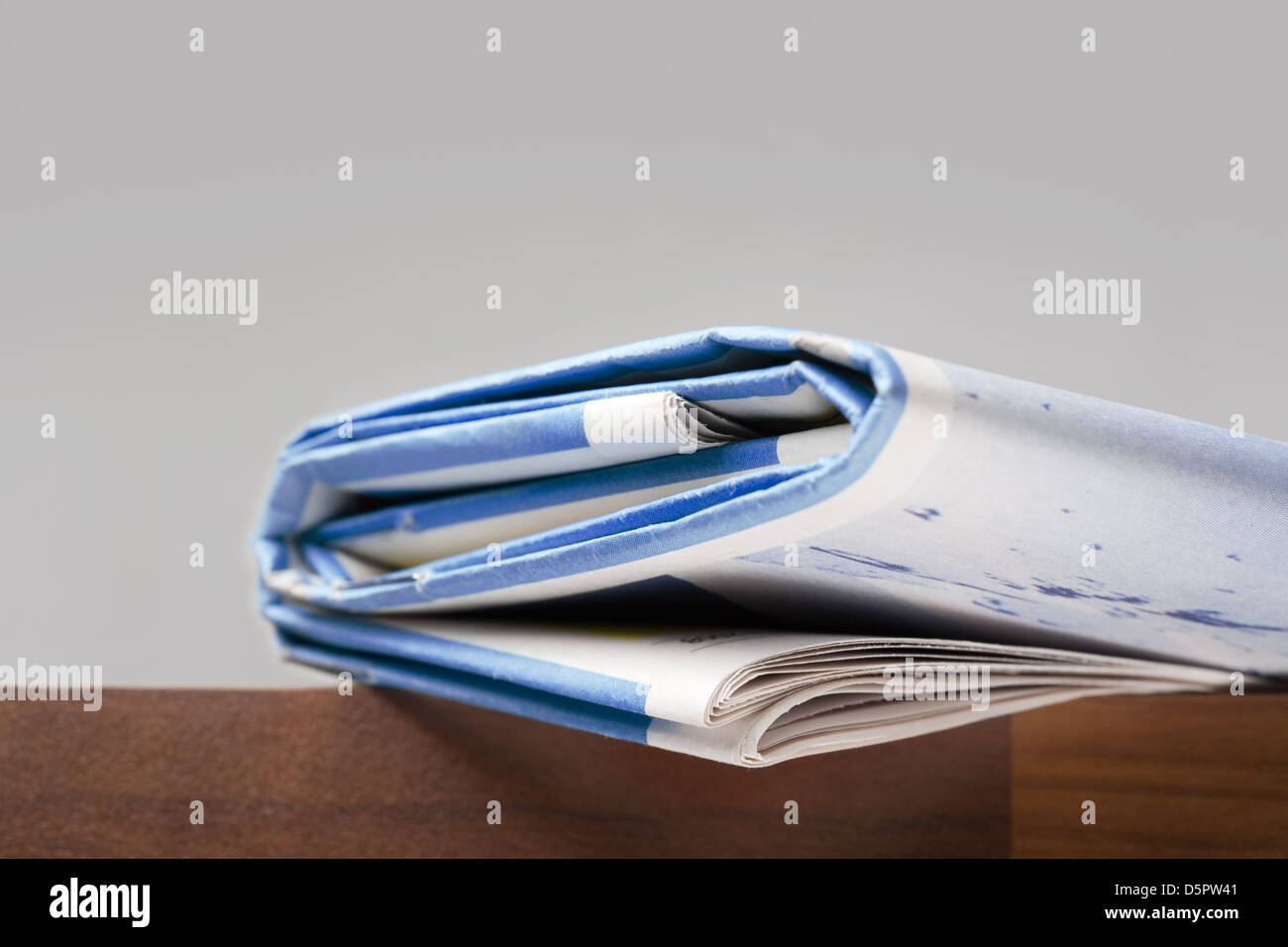 Folded newspapers on brown wooden table Stock Photo - Alamy