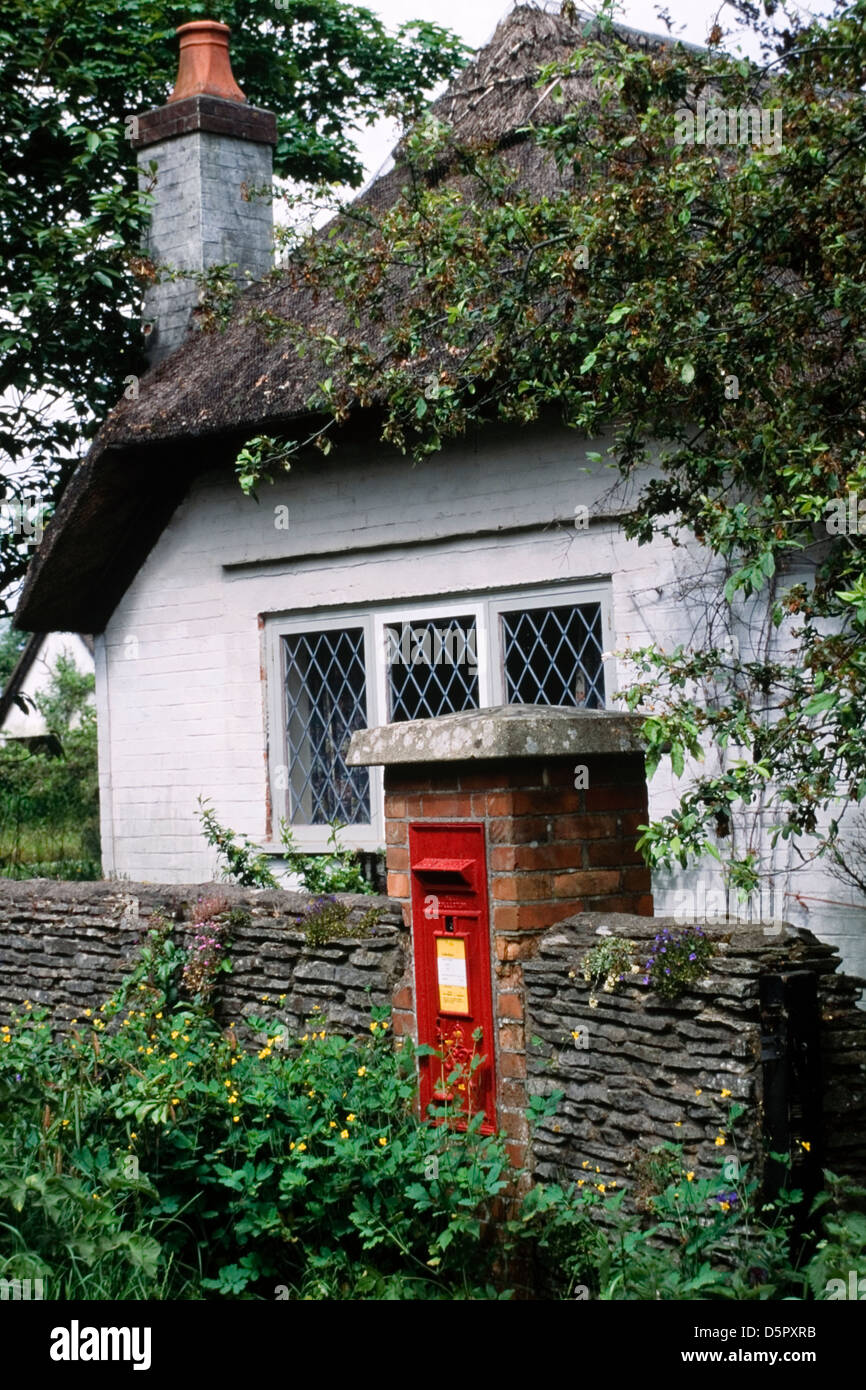 rural post box built into a brick wall in front of traditional thatched ...