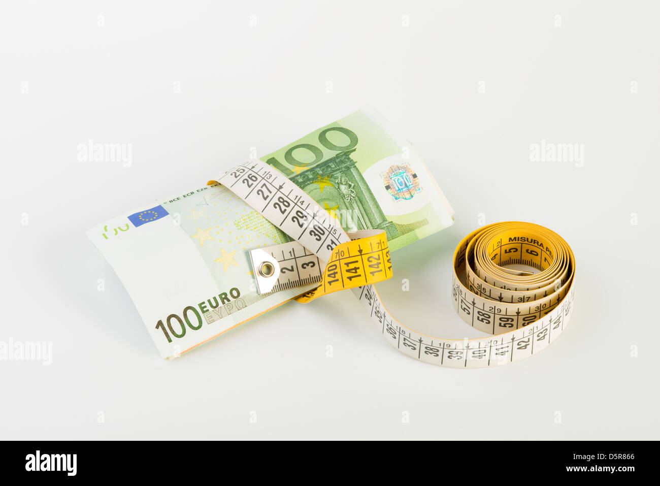 a yellow tape measure wrapped around euro's banknotes Stock Photo - Alamy