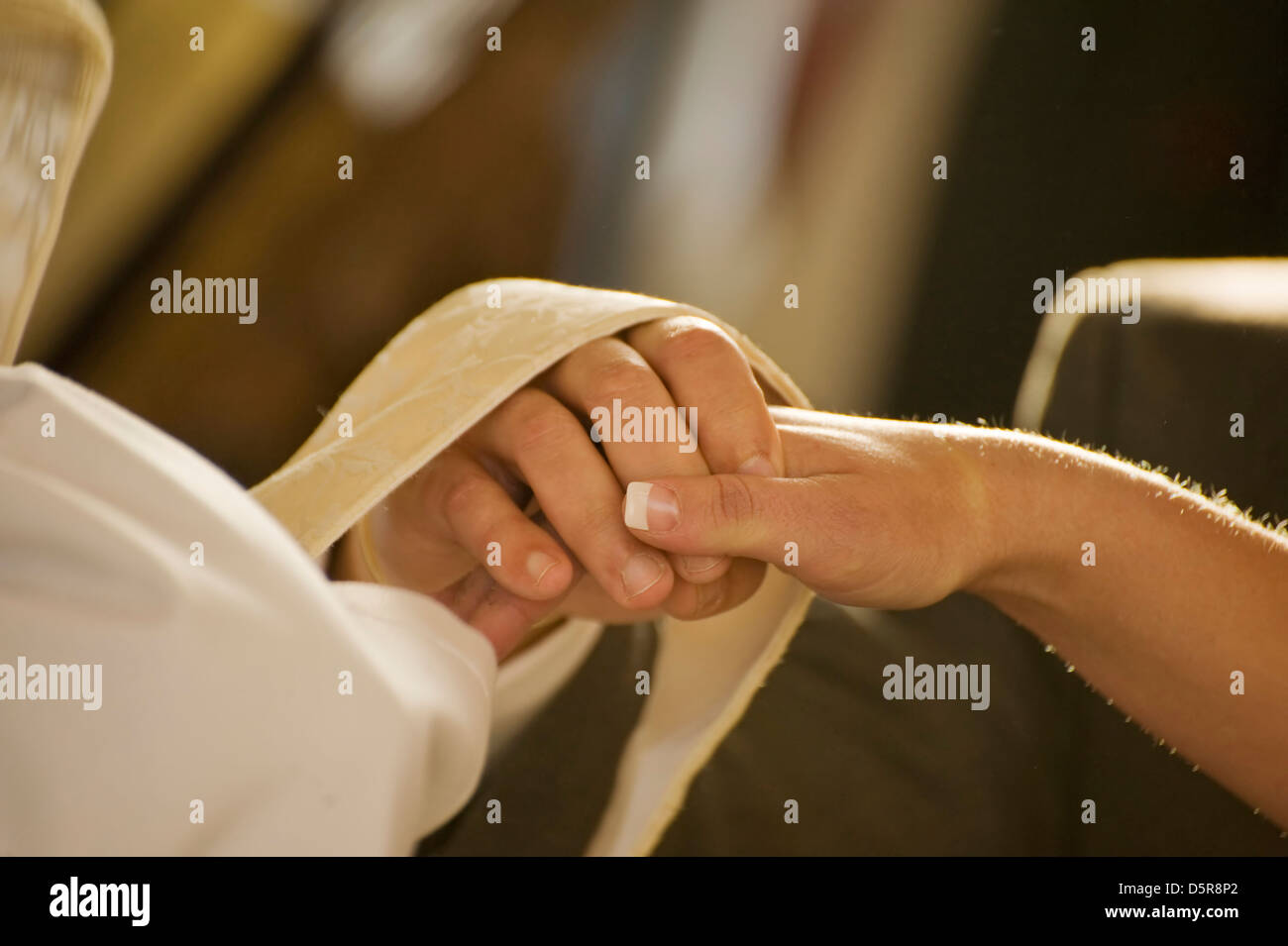 Close up of bride and groom having rings blessed during real wedding ...