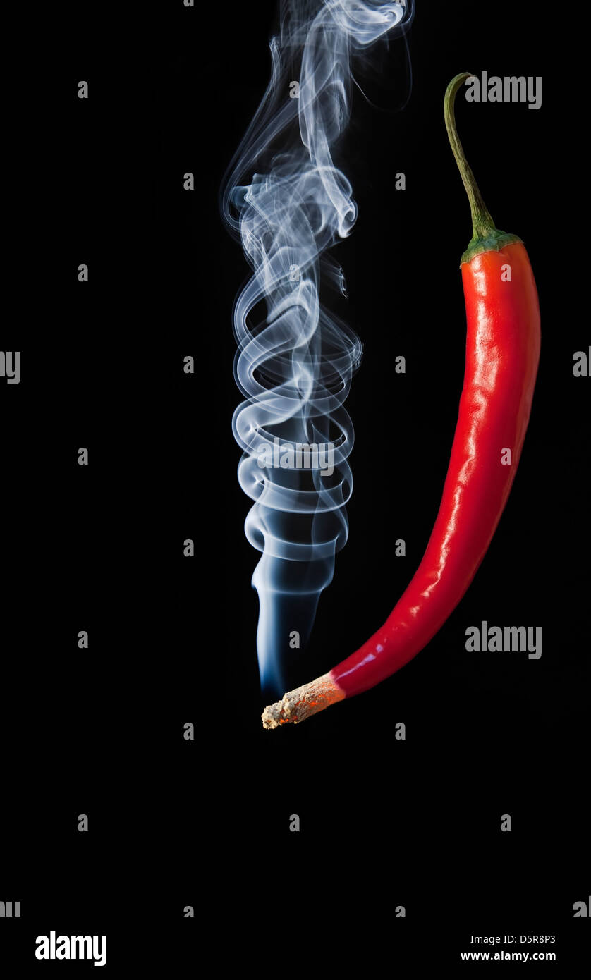 Red hot chilli pepper with smoke coming out of tip which is burning and ...