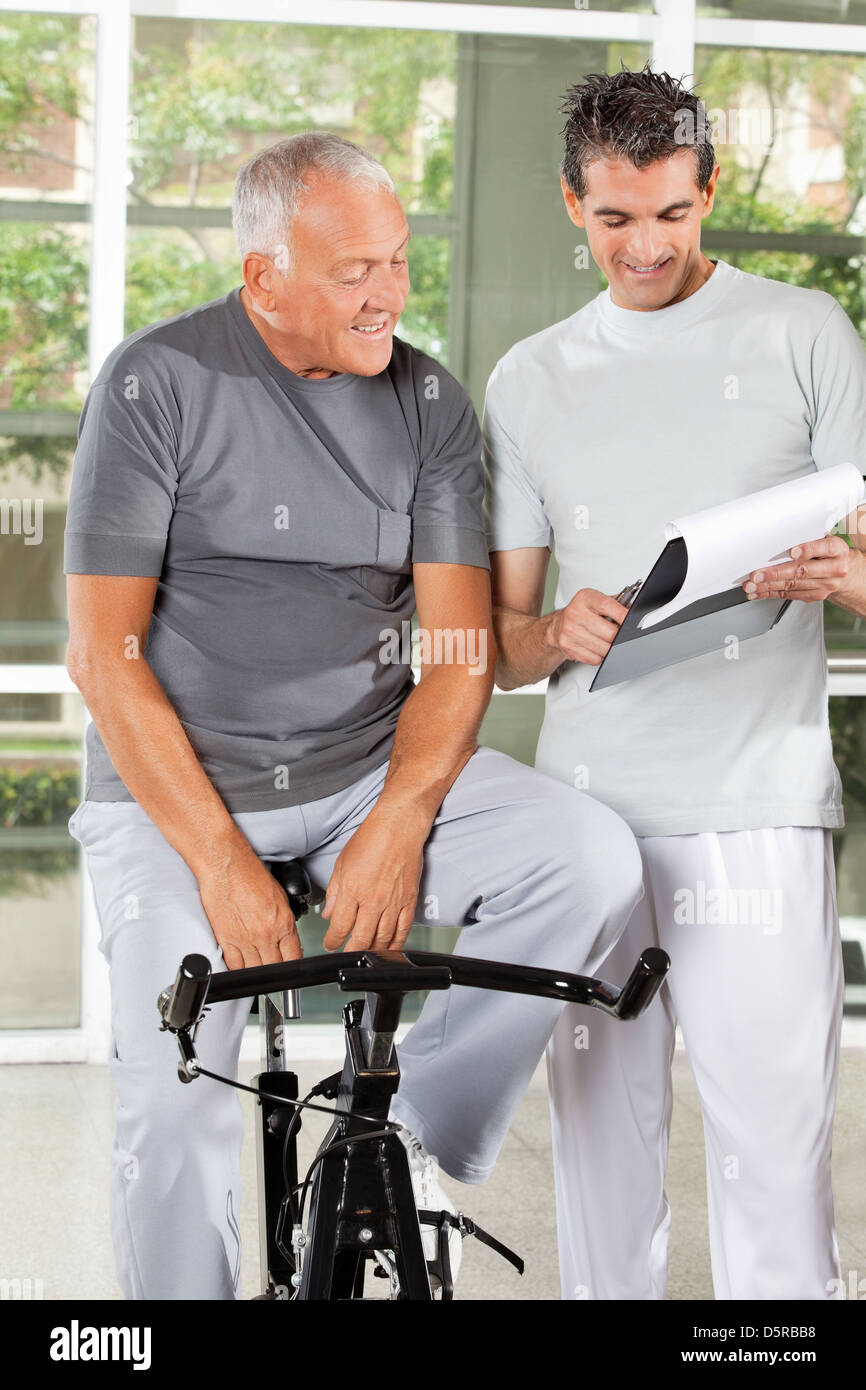 Fitness coach explaining training plan to senior man in gym Stock Photo ...