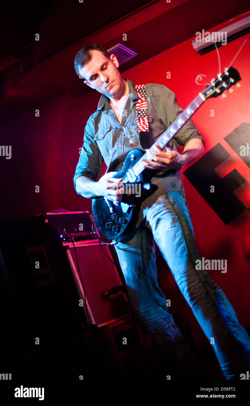 musician plays a guitar on a red background Stock Photo - Alamy