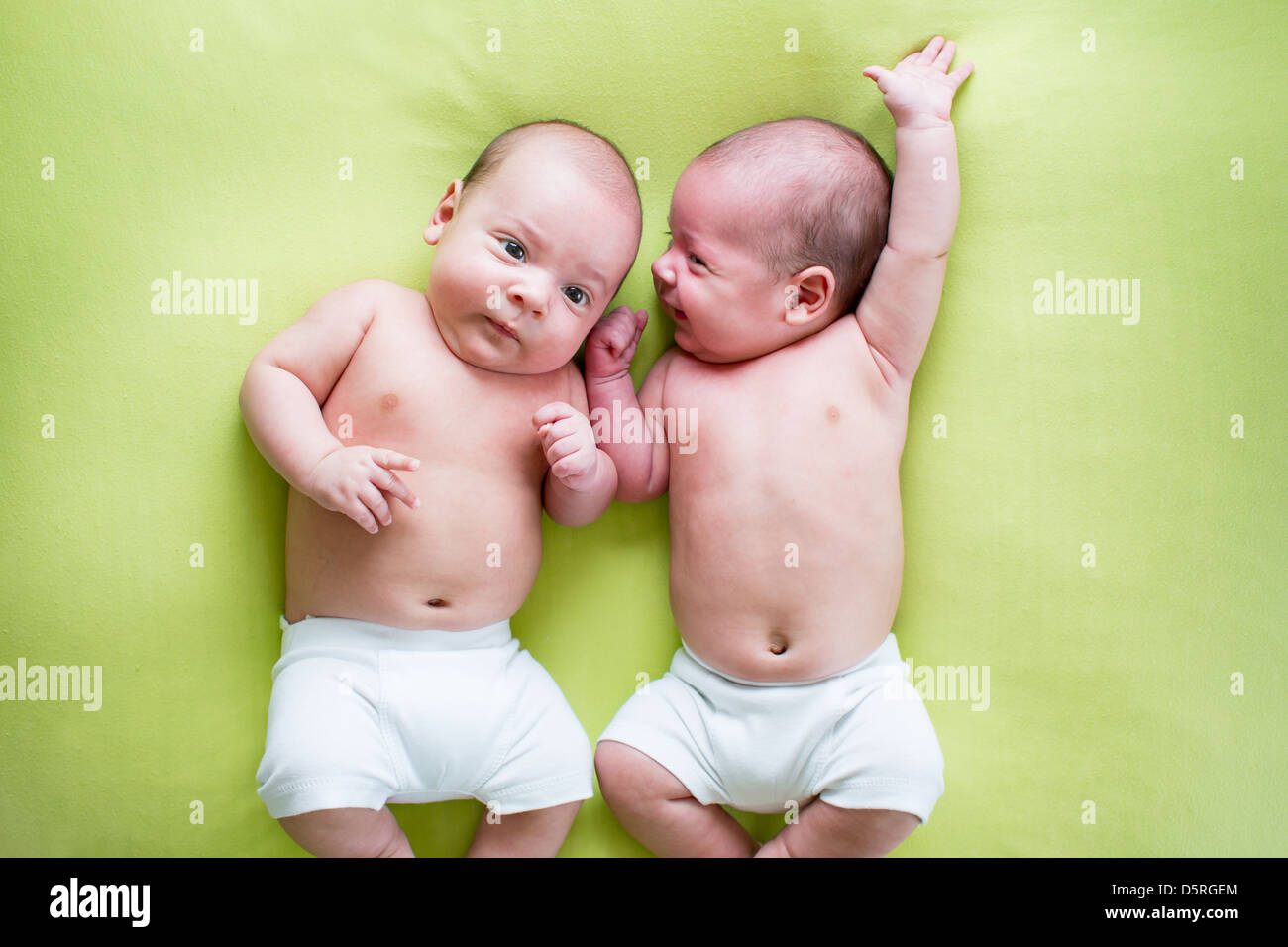 funny twins brothers babies lying on green Stock Photo - Alamy