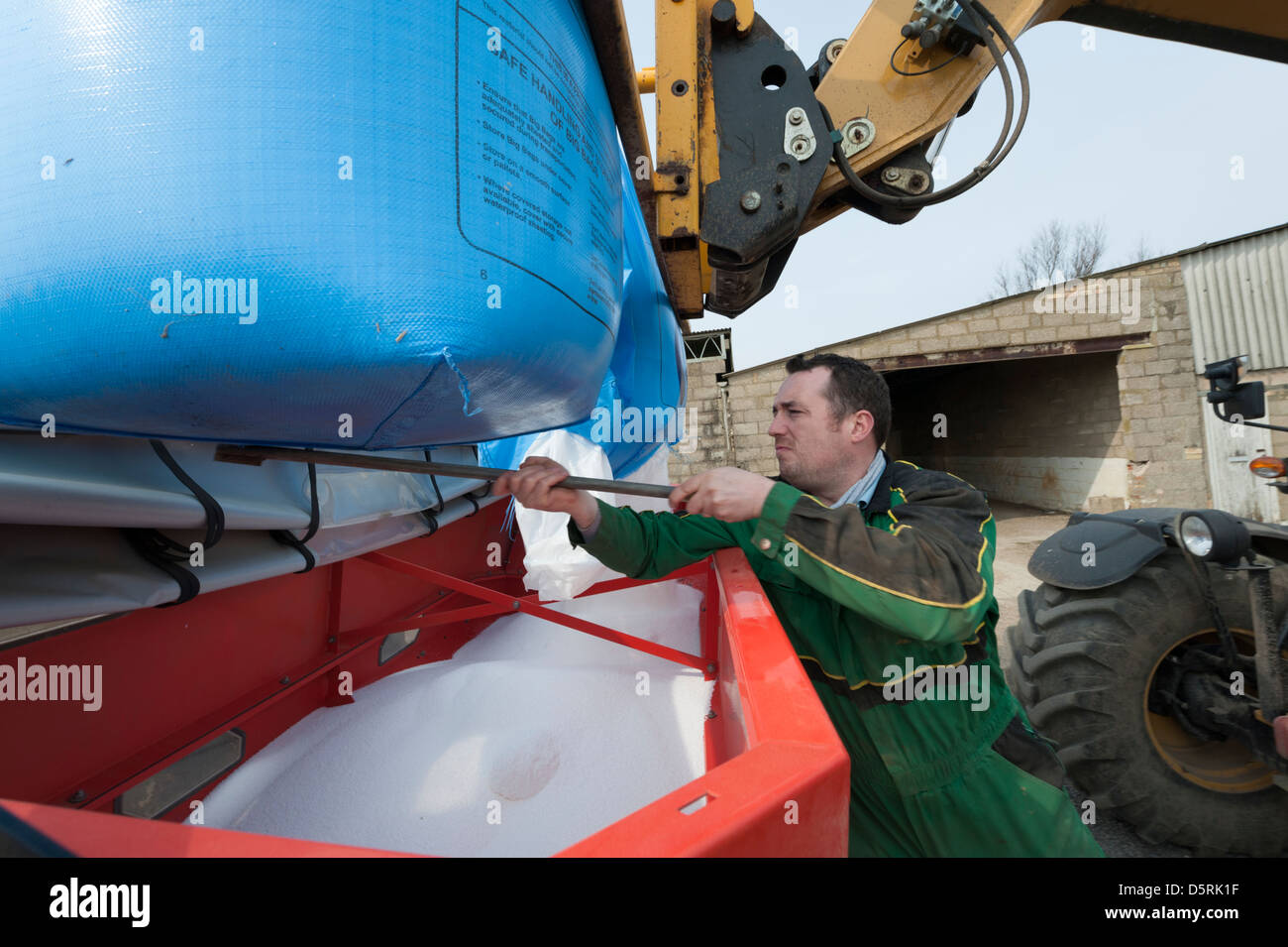 A farmer loading nitrogen fertiliser into a spreading machine ready for ...