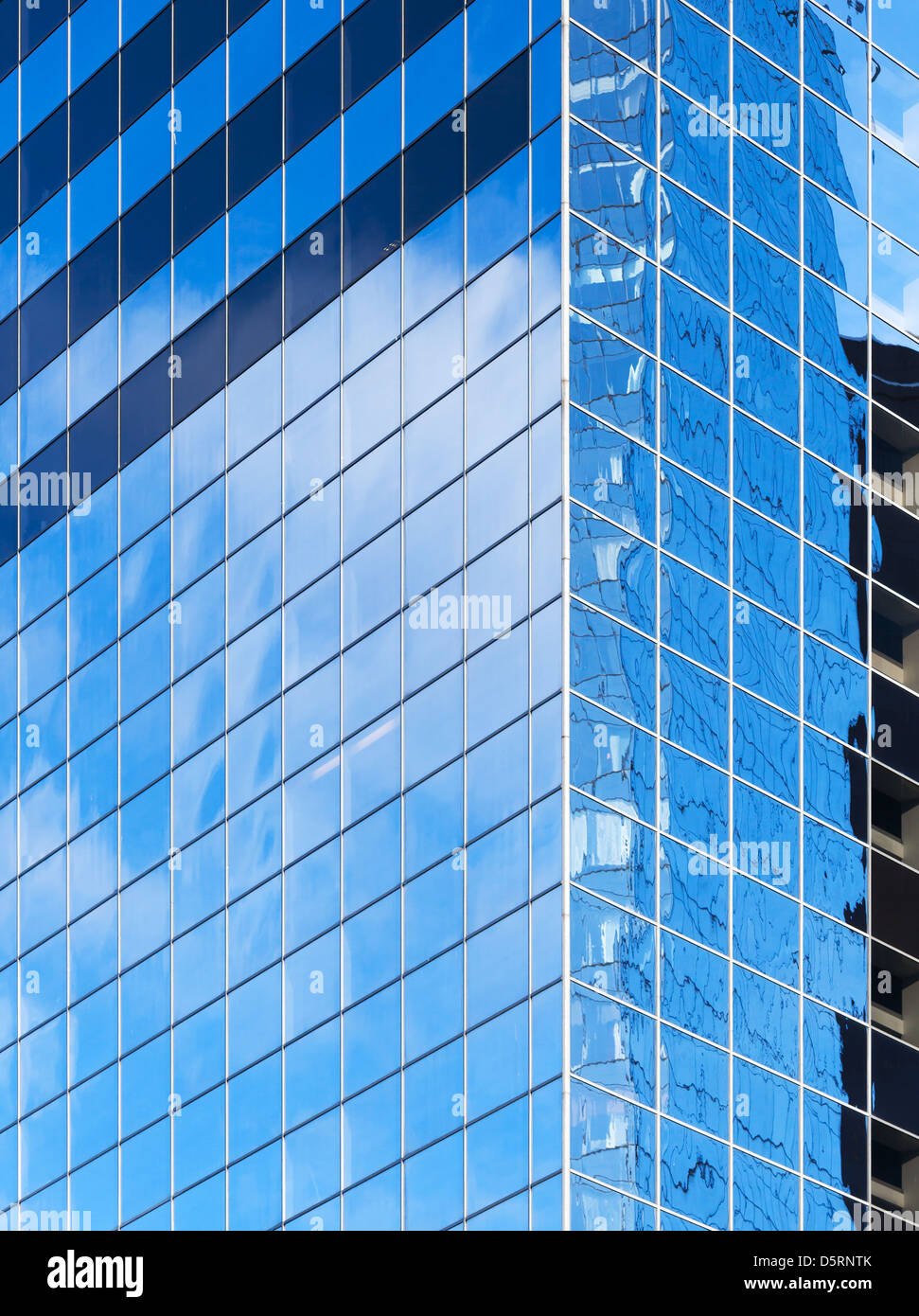 Vertical corner of modern office building with bright blue sky ...
