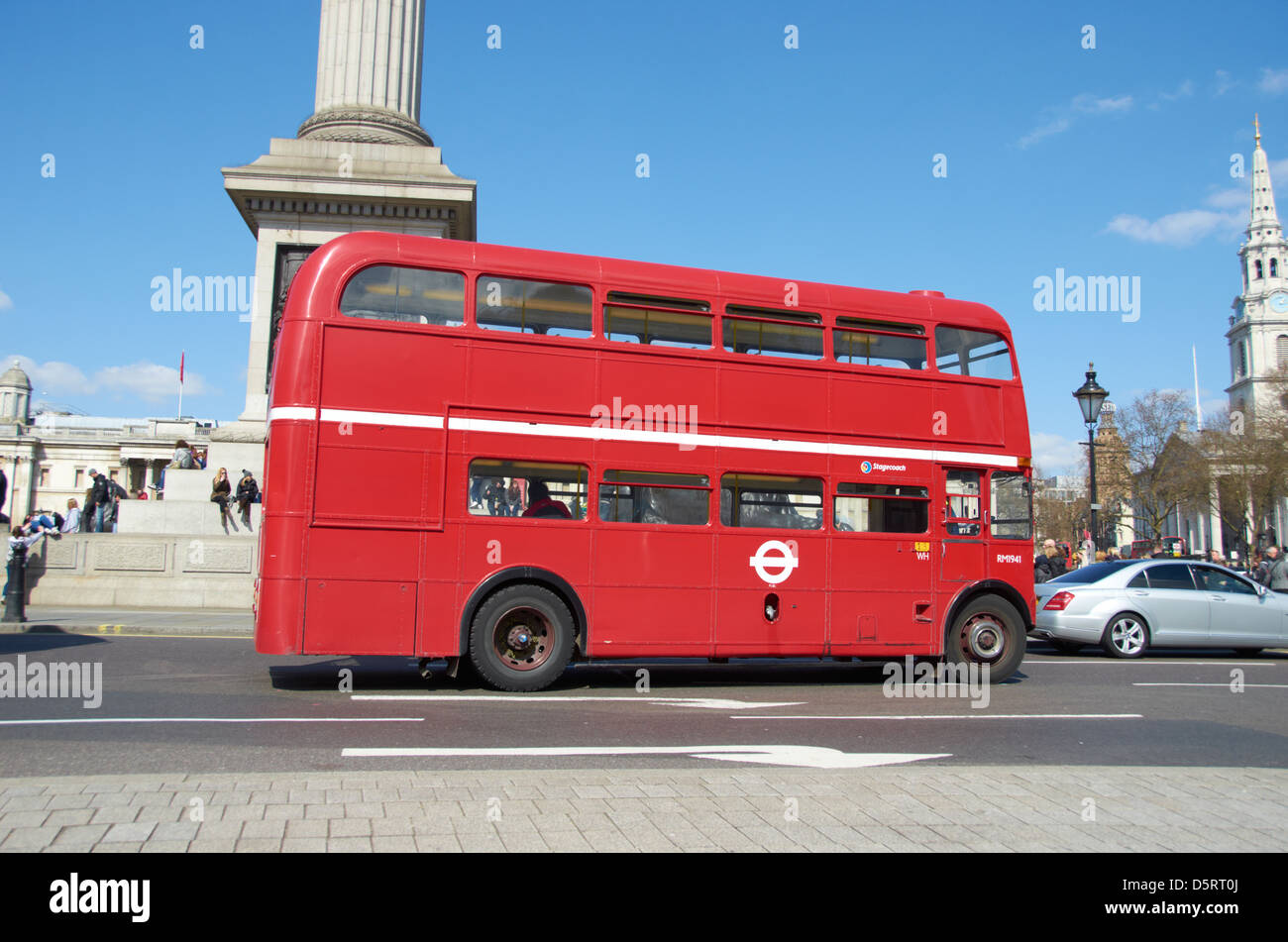 Red London Bus driving around Trafalgar Square, London, England with ...