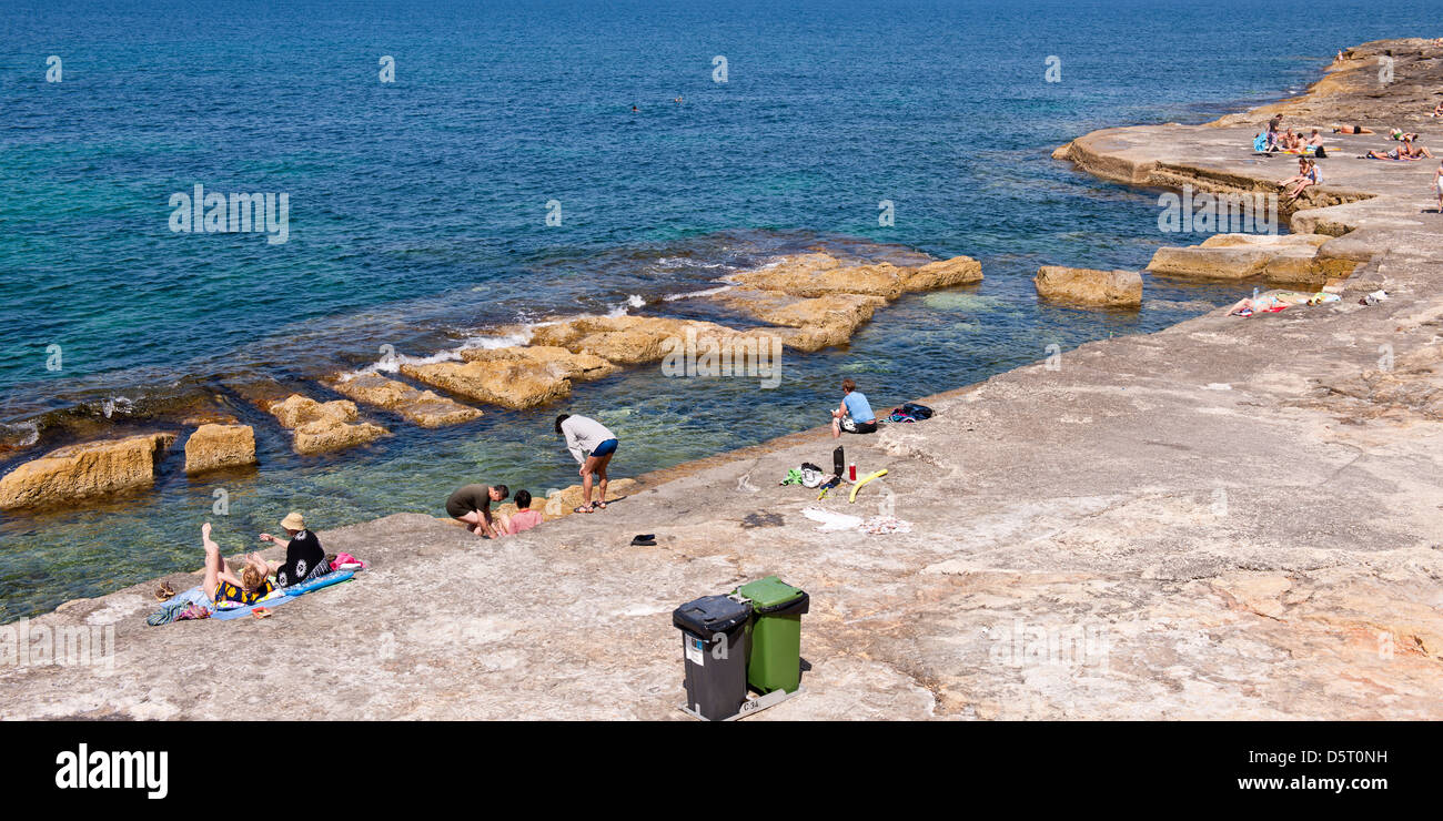 People swimming and sunbaking on the rocks at Sliema, Malta Stock Photo ...