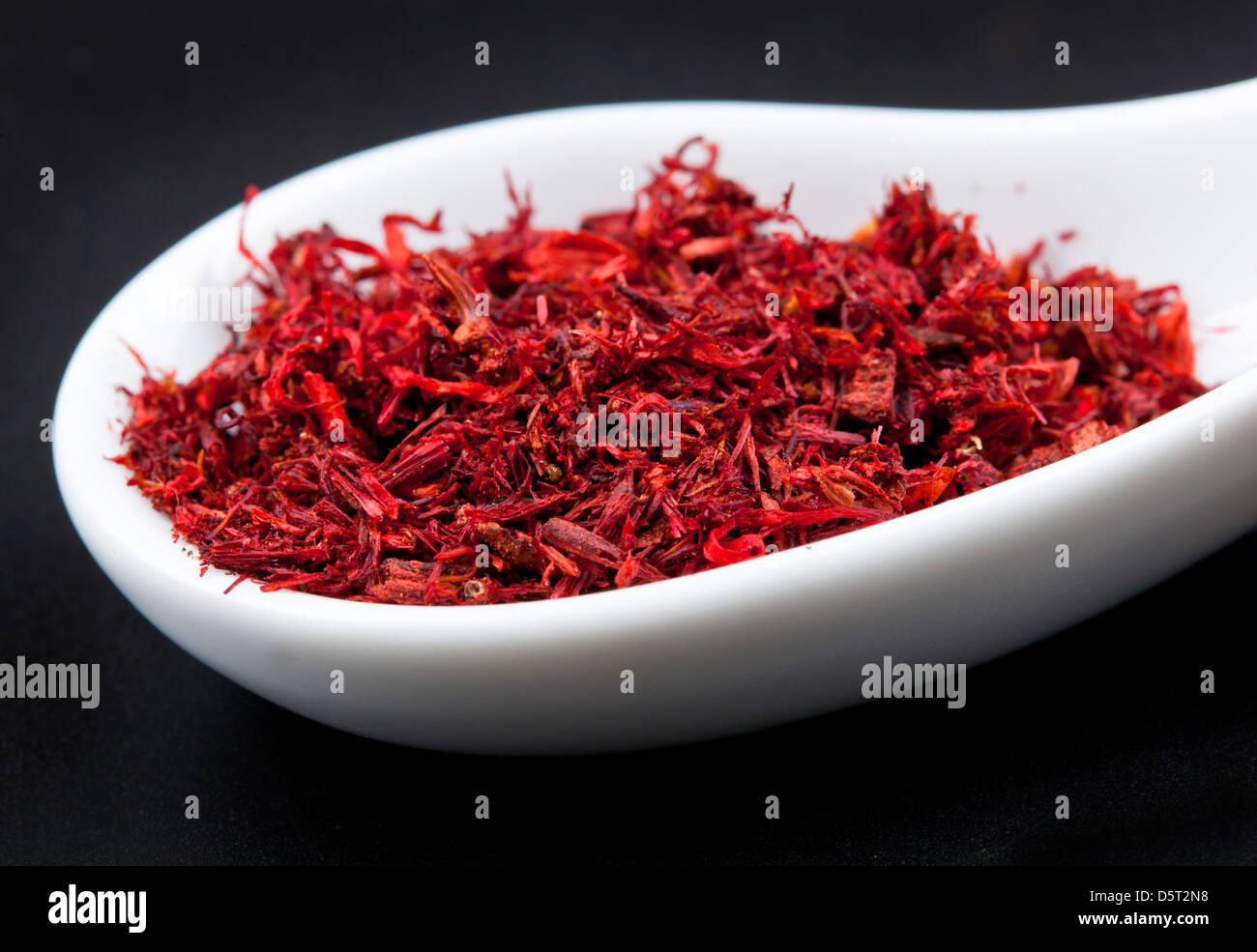 Saffron in white spoon on black table Stock Photo - Alamy