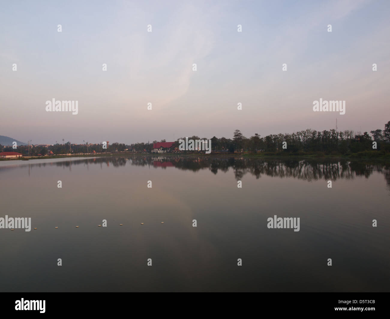 Morning breaks over the glassy still lake and tree background Stock ...