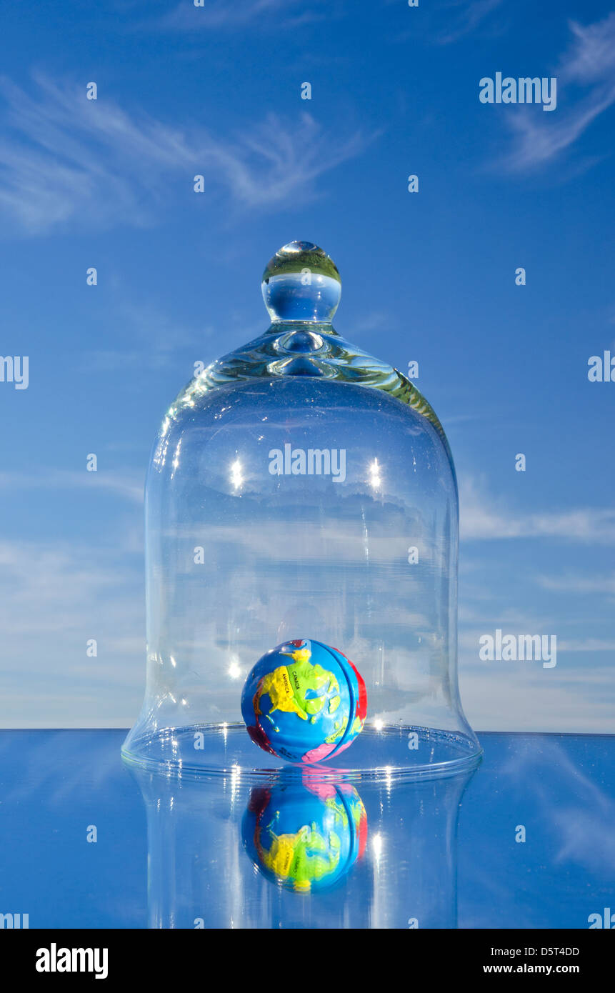 small Earth globe toy in glass bell on mirror in space.Safety concept ...