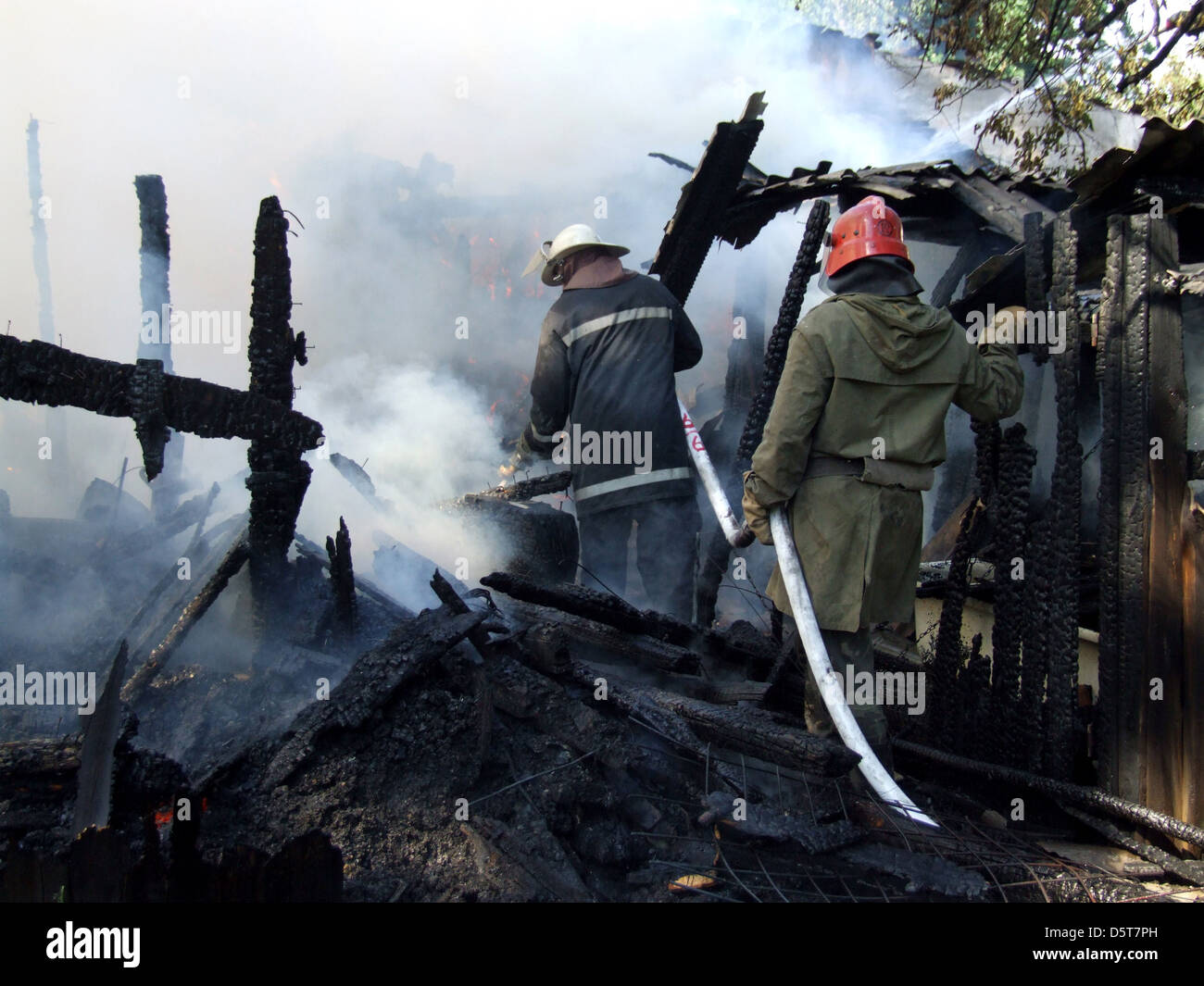 Smoldering remains of a ghetto house with a fireman spraying water ...