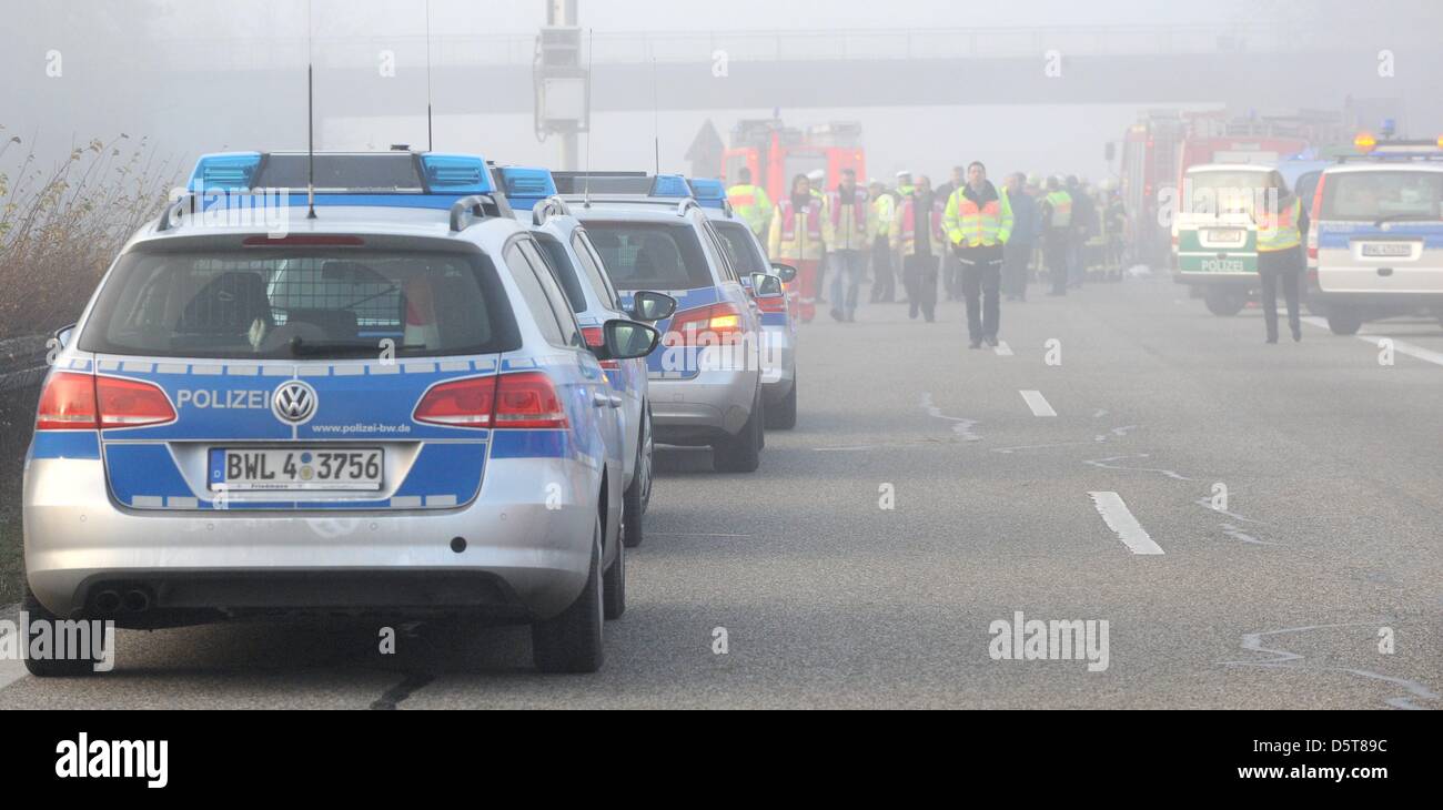Police officers and fierfighters stand in front of cars involved in an ...