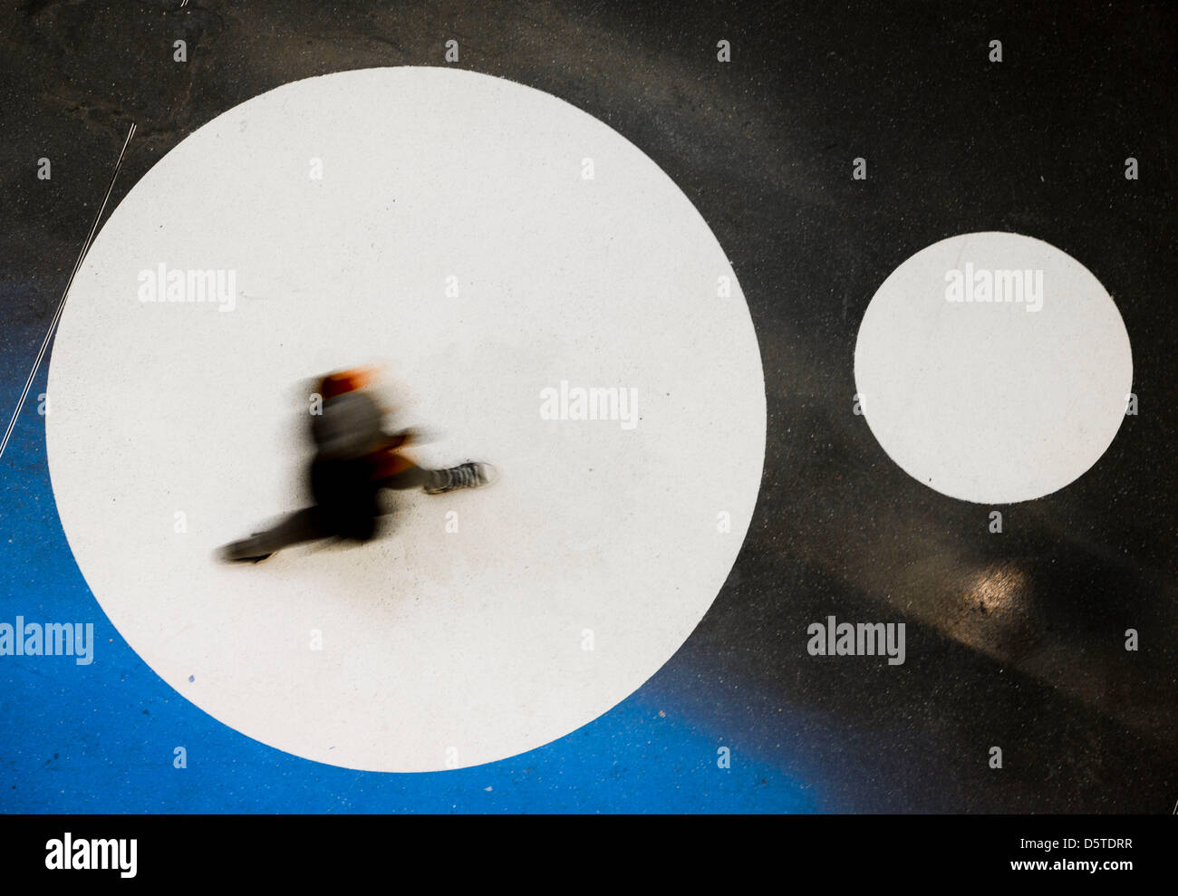 A young man walks across two white dots on the floor of a shopping ...