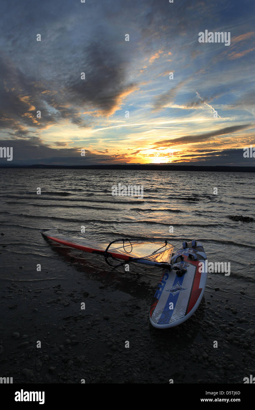 Surfboard with sail lies on the shore at the Ammersee near Herrsching ...
