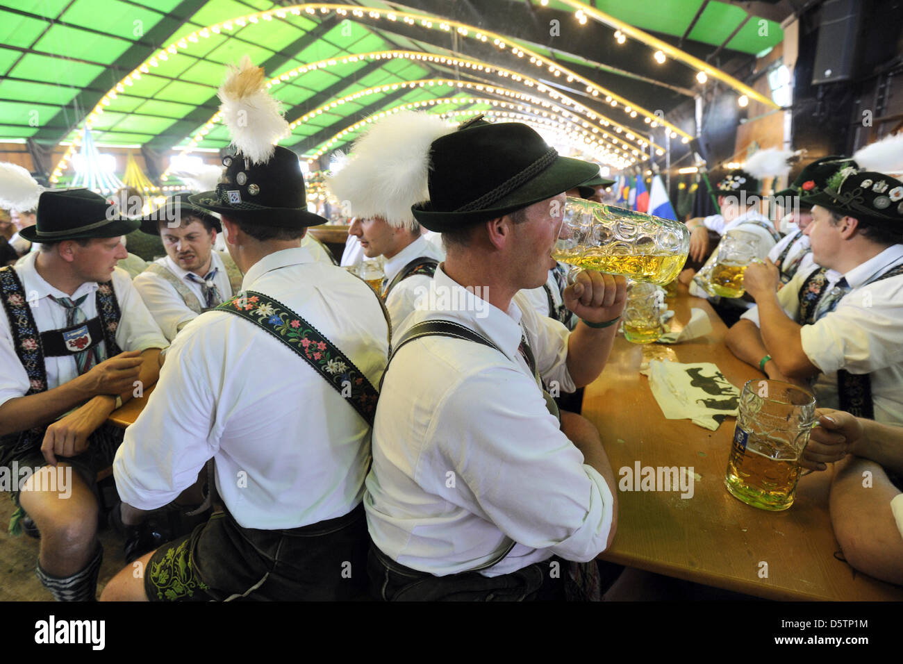 Visitors dressed in traditional Bavarian clothes sit inside a tent at ...