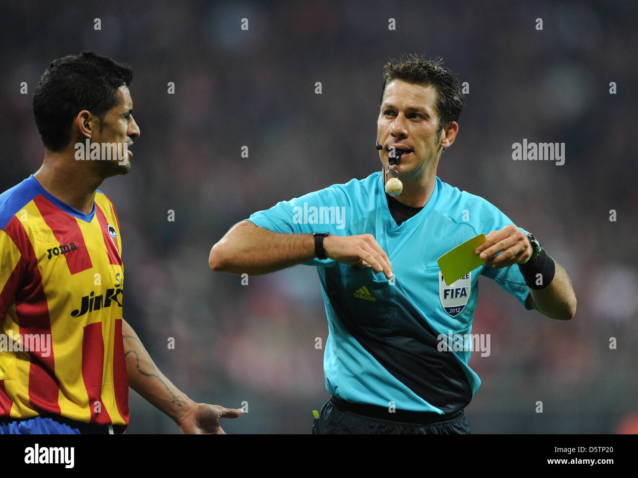 Referee Firat Aydinus (R) shows the yellow card to Valencia's Adil Rami ...