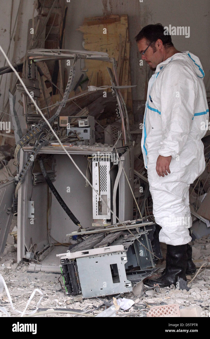 A forensic scientist stands in front of a destroyed cash machine at a ...