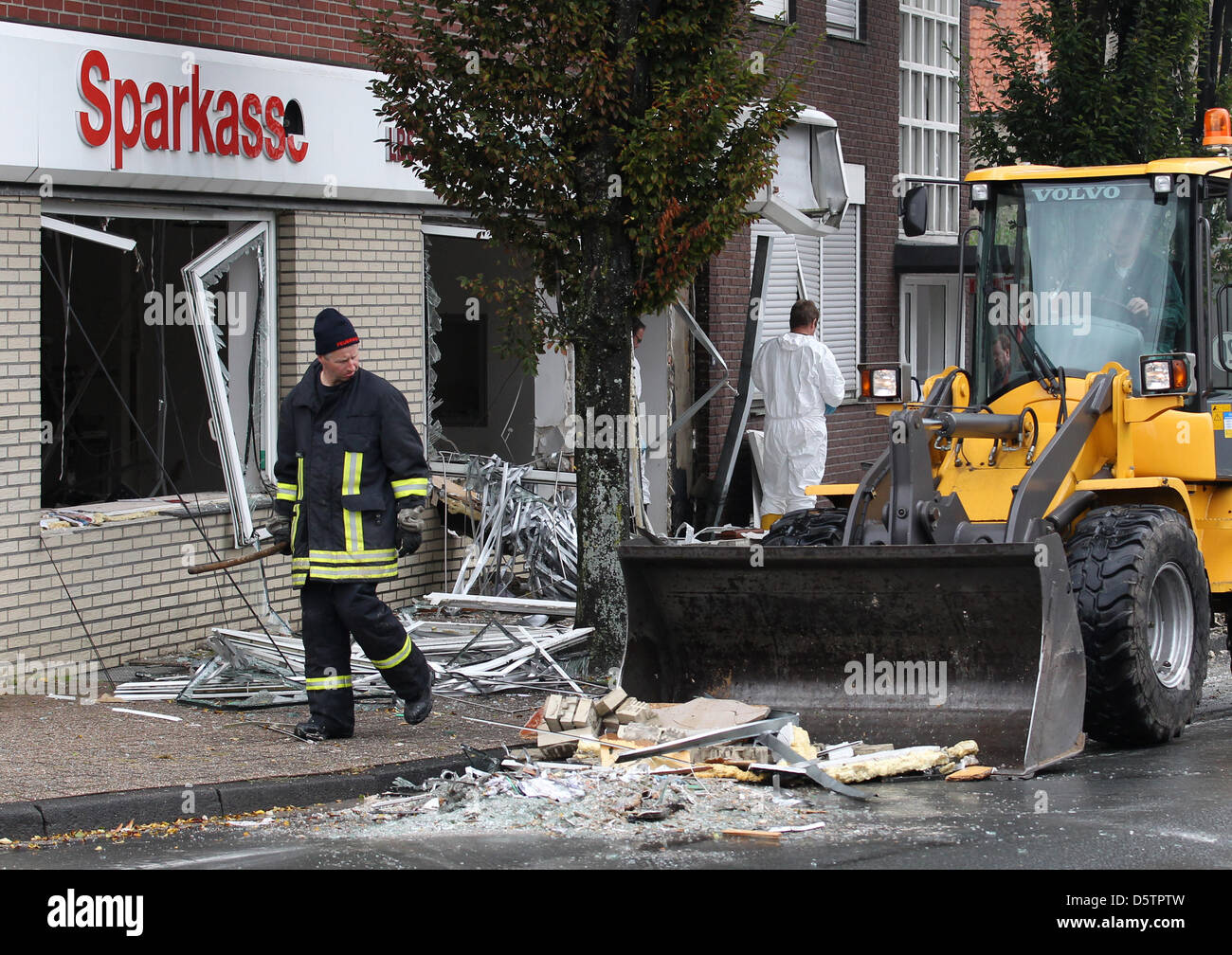 Debris and parts of a building are cleared of the street after an ...