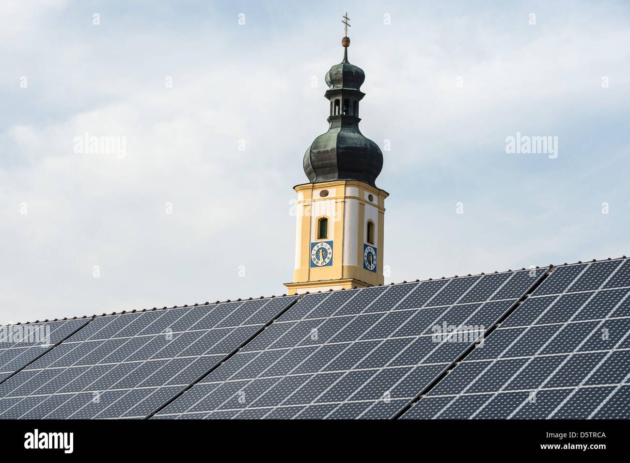 Solar panels on top of a house are pictured in front of a church tower ...