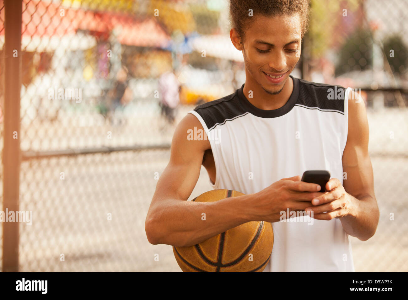 Man using cell phone on basketball court Stock Photo - Alamy