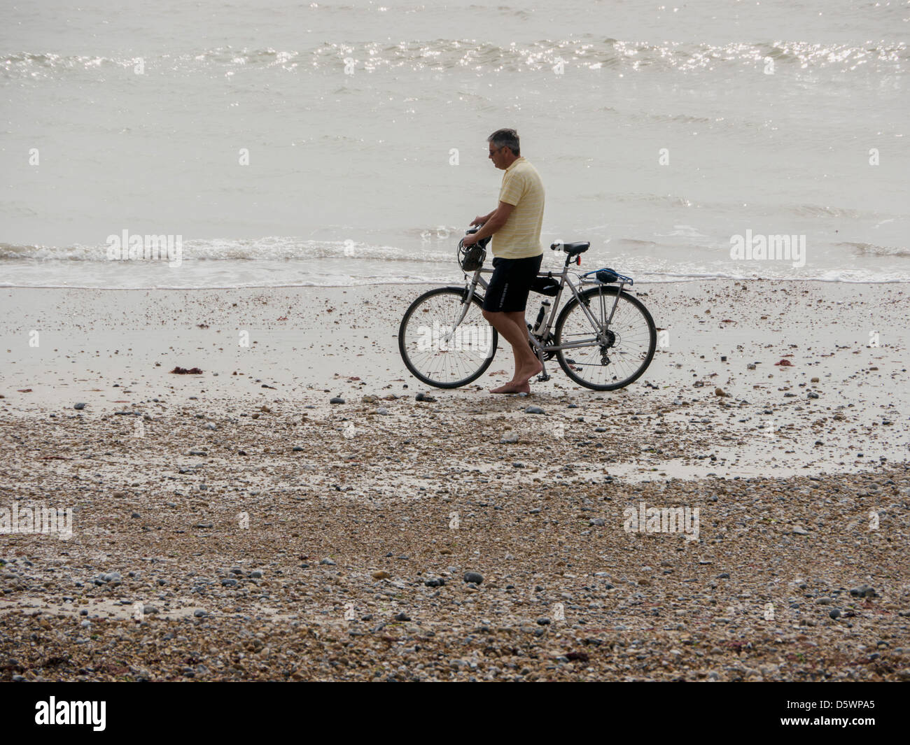 man pushing bicycle along beach Stock Photo - Alamy