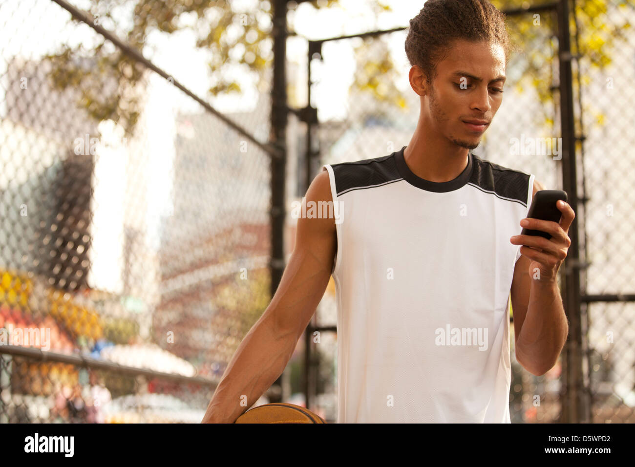 Man using cell phone on basketball court Stock Photo - Alamy