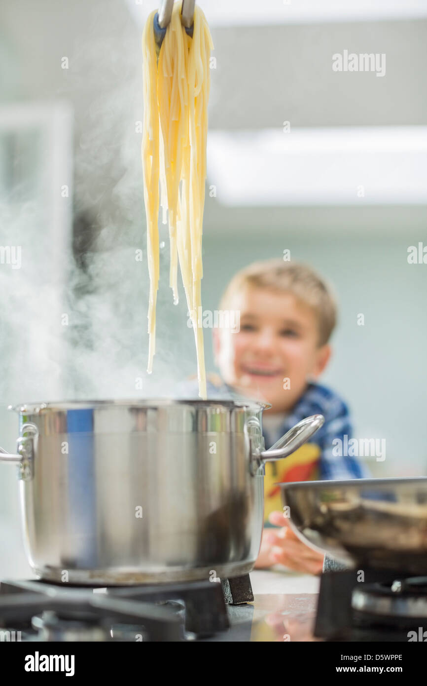 Boy watching parent cook spaghetti Stock Photo - Alamy
