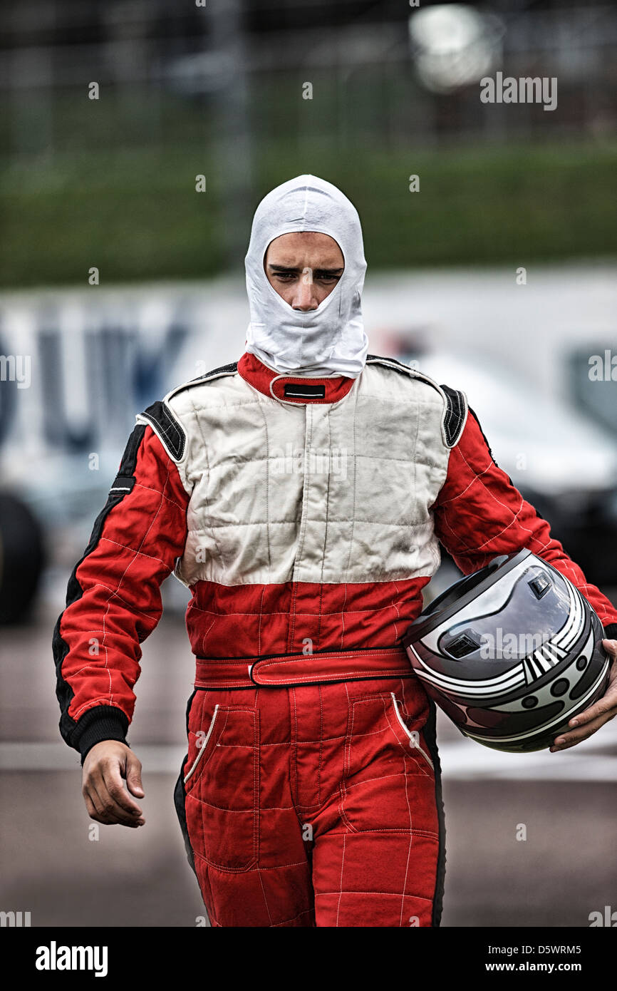 Racer carrying helmet on track Stock Photo - Alamy