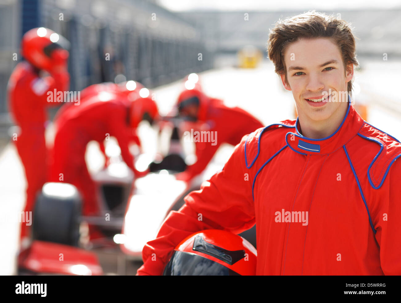 Racer holding helmet on track Stock Photo - Alamy