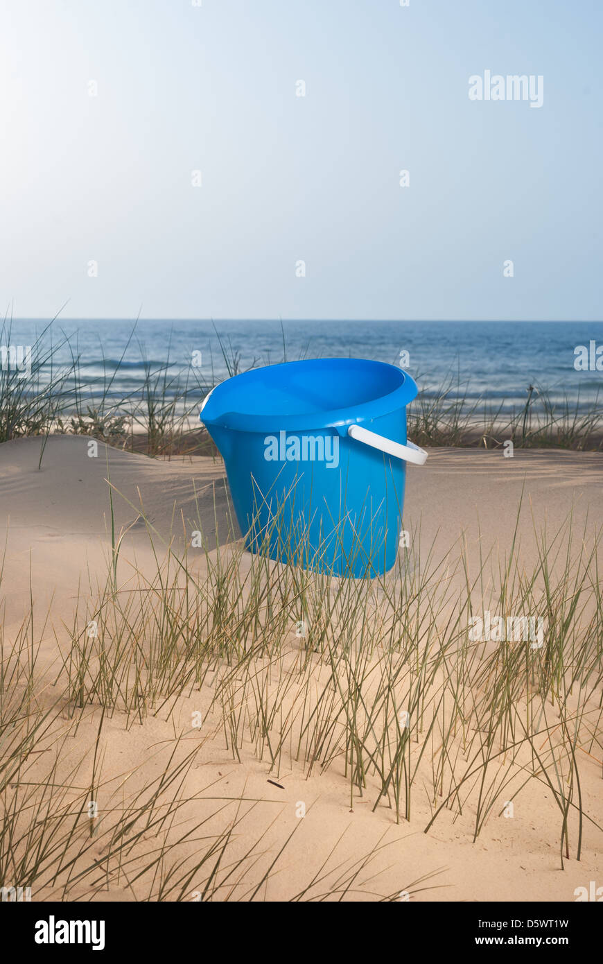 Blue bucket standing on sand at the beach at sunset Stock Photo - Alamy