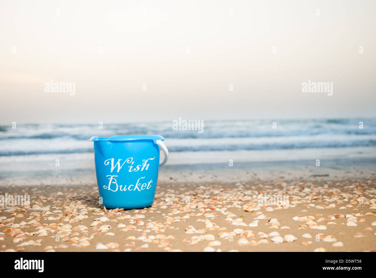 Blue bucket standing on sand at the beach at sunset Stock Photo - Alamy
