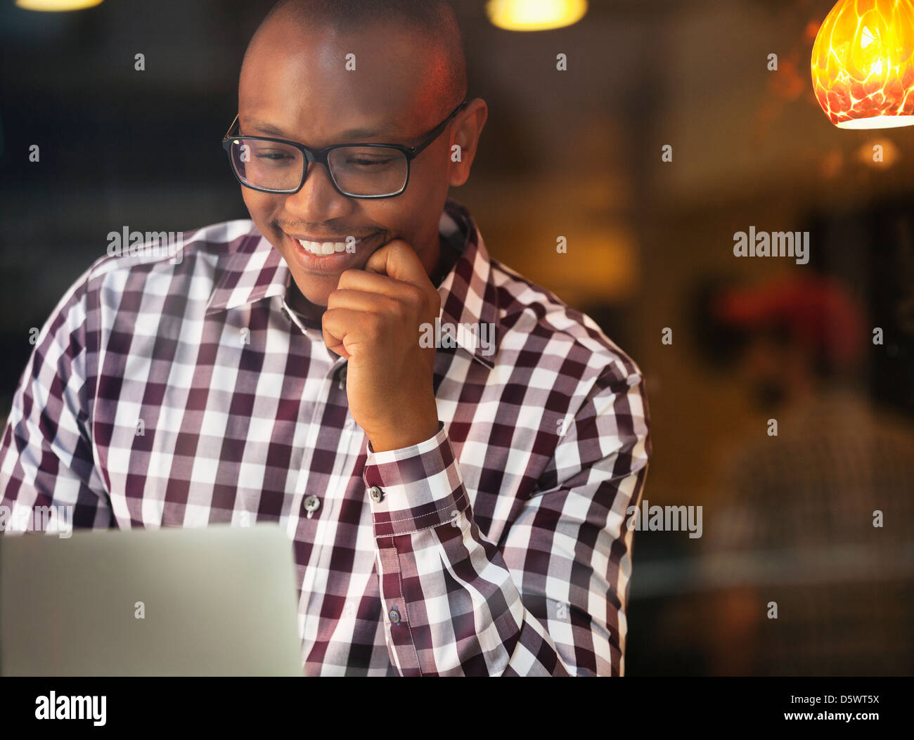Smiling man reading laptop indoors Stock Photo - Alamy