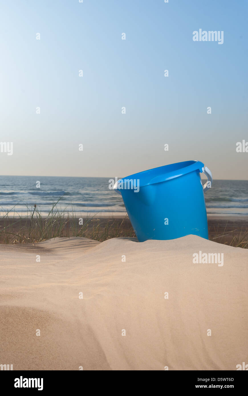 Blue bucket standing on sand at the beach at sunset Stock Photo - Alamy