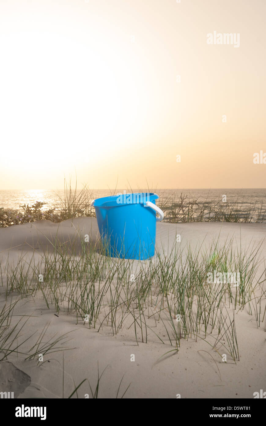 Blue bucket standing on sand at the beach at sunset Stock Photo - Alamy