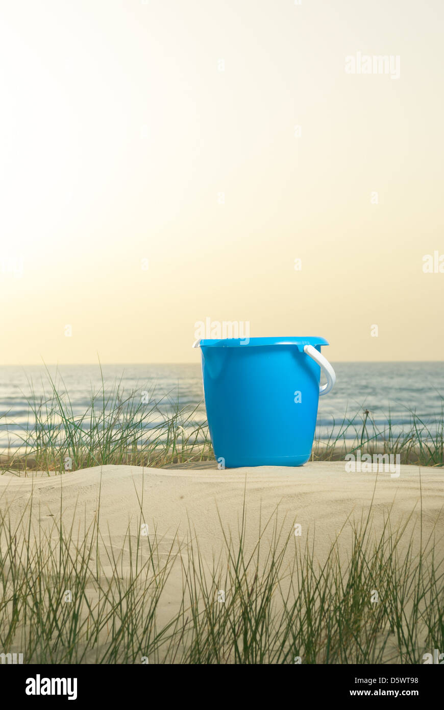 Blue bucket standing on sand at the beach at sunset Stock Photo - Alamy
