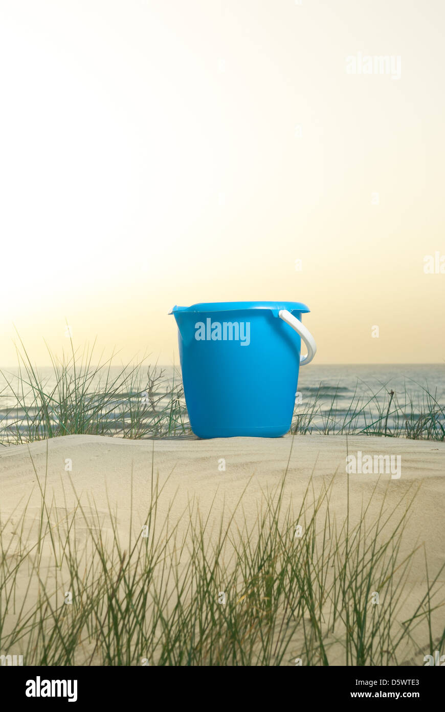 Blue bucket standing on sand at the beach at sunset Stock Photo - Alamy