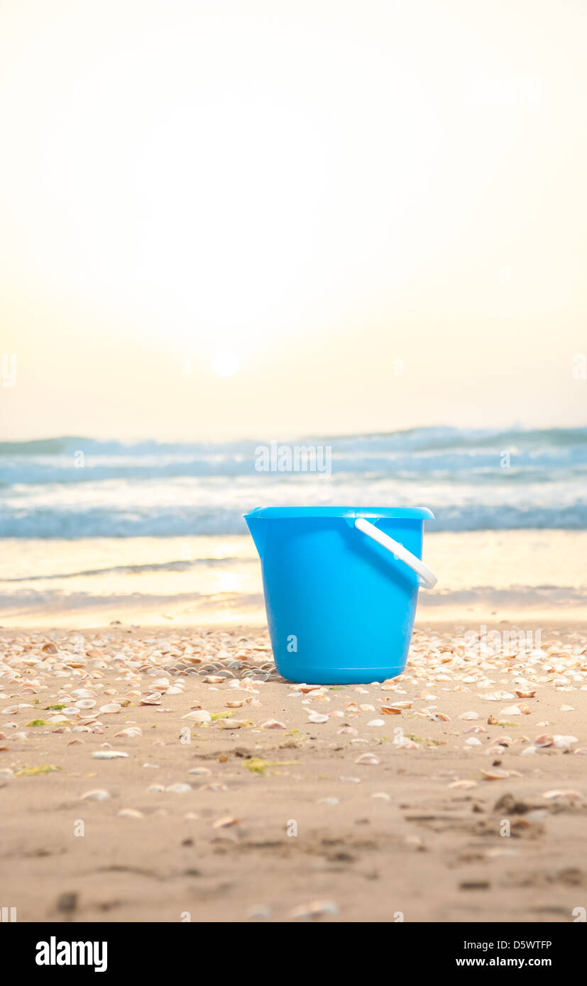 Blue bucket standing on sand at the beach at sunset Stock Photo - Alamy