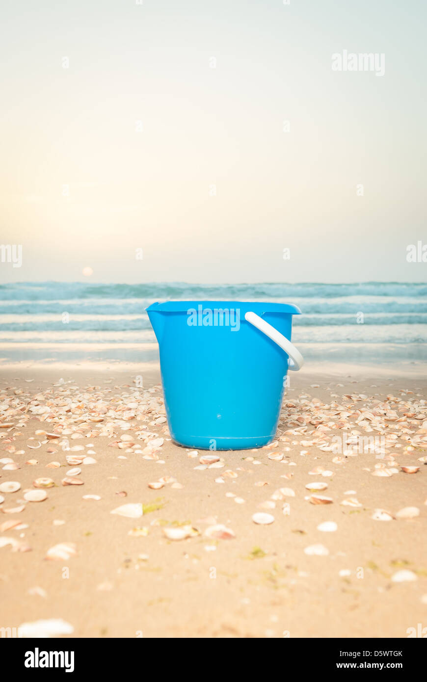 Blue bucket standing on sand at the beach at sunset Stock Photo - Alamy
